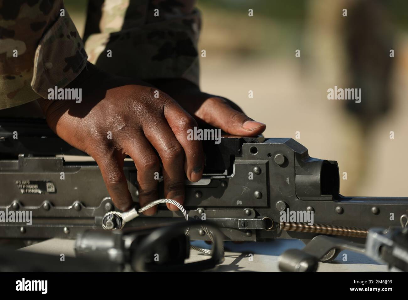 A U.S. Army soldier installs the feed tray cover on an M240 machine gun ...