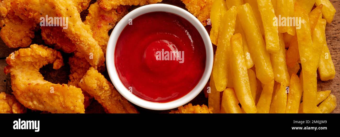 Chicken tenders panorama, crispy boneless meat pieces with a red dip ...