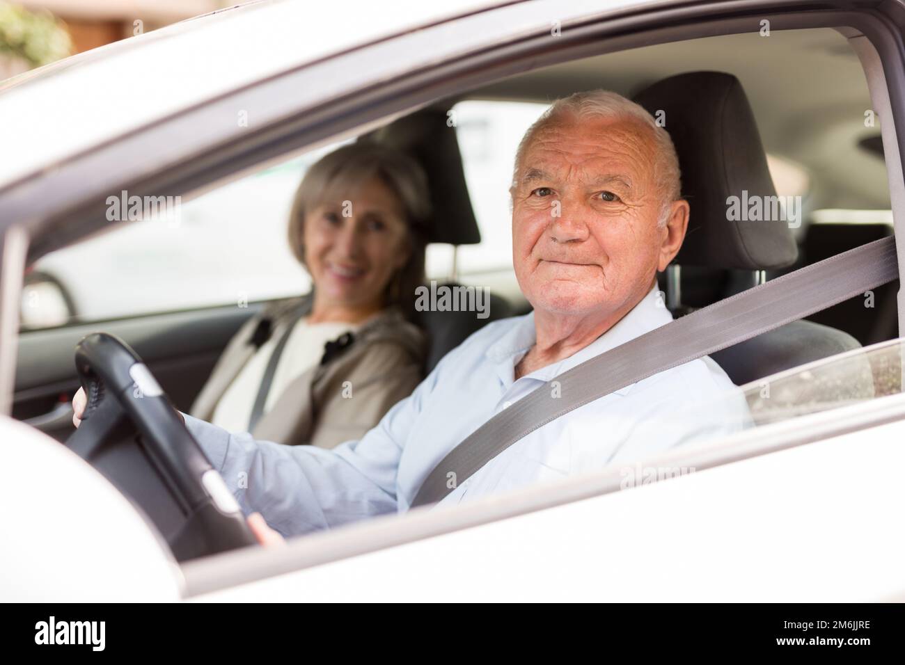 Elderly man and woman driving a car in the city. Man driving car Stock ...