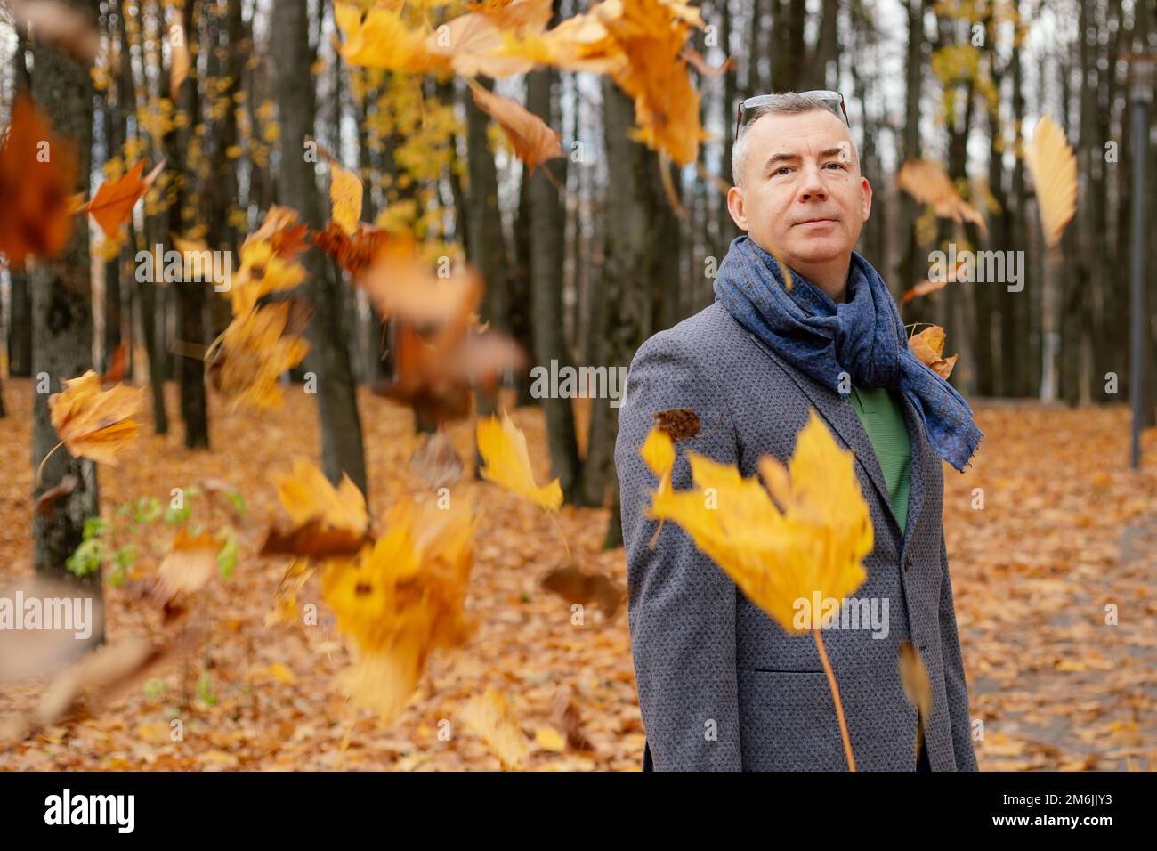 Portrait of handsome middle-aged man standing near trees among flying ...
