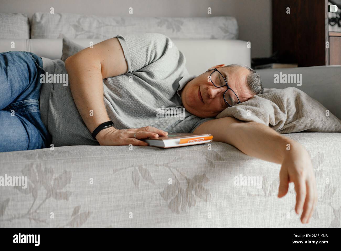 Portrait of smiling middle-aged man lying with closed eyes, stretching ...