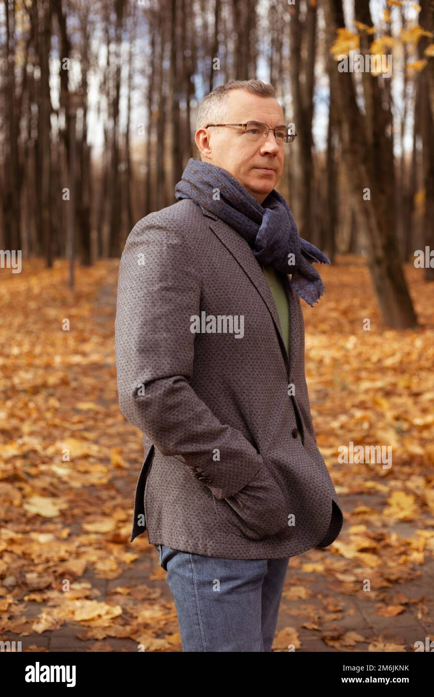 Portrait of middle-aged man standing, putting hands into pockets near ...