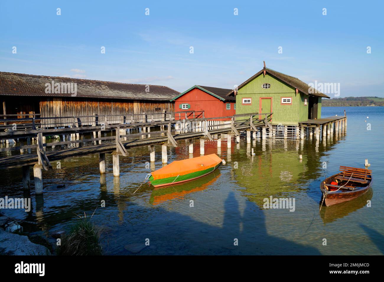 a long wooden pier leading to the colorful boat houses on lake Ammersee ...