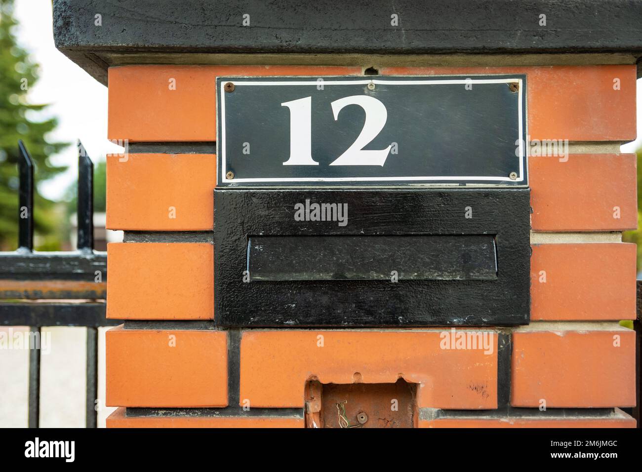 House number 12 above letterbox in red fence Stock Photo - Alamy