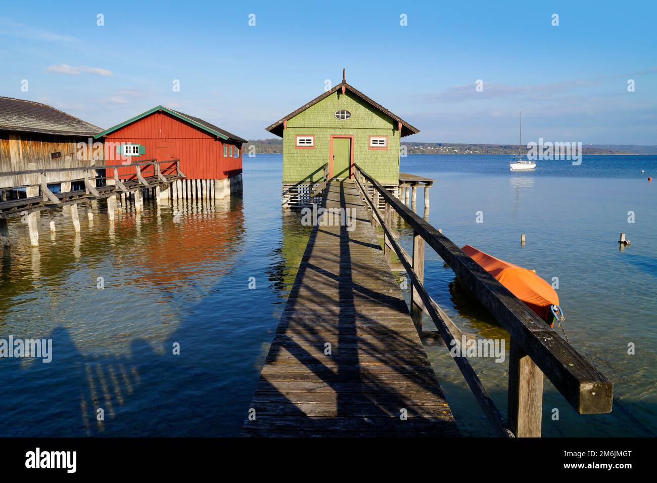 a long wooden pier leading to the colorful boat houses on lake Ammersee ...