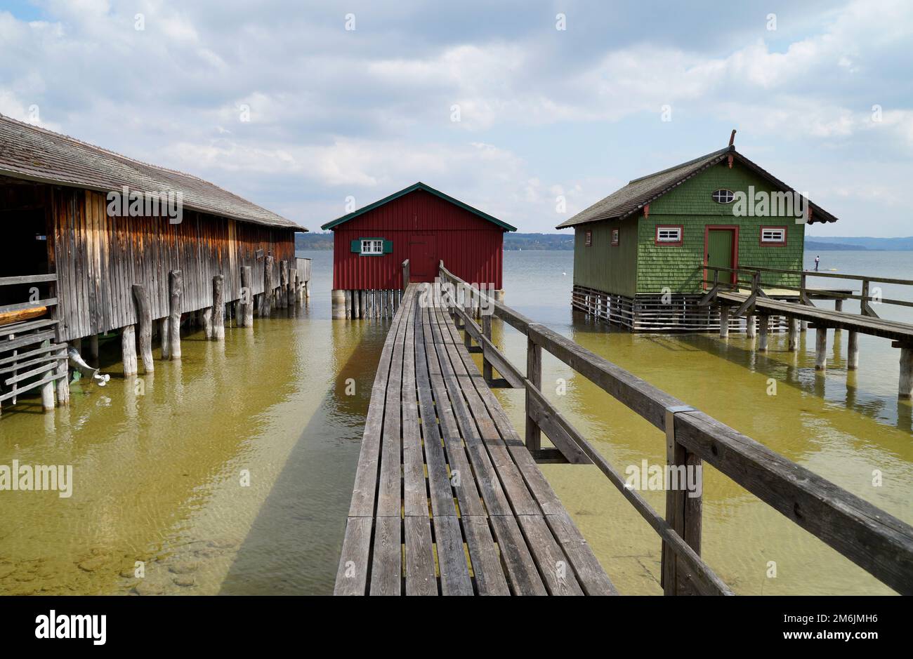 a long wooden pier leading to the colorful boat houses on lake Ammersee ...
