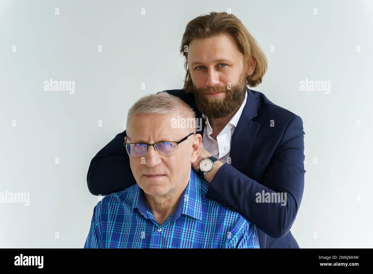 The son in a stylish suit leans on the shoulders of his father, Father ...