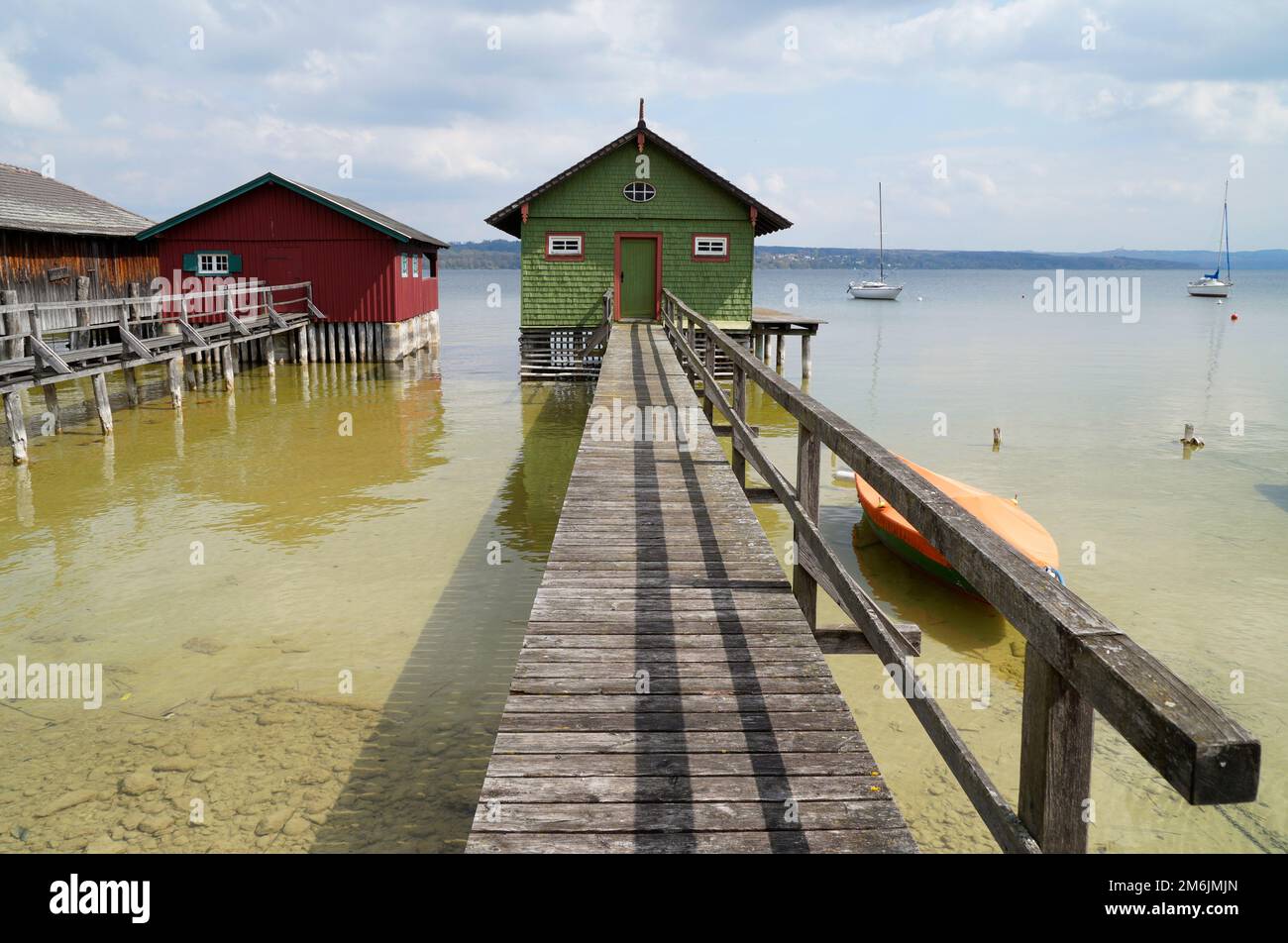 a long wooden pier leading to the colorful boat houses on lake Ammersee ...