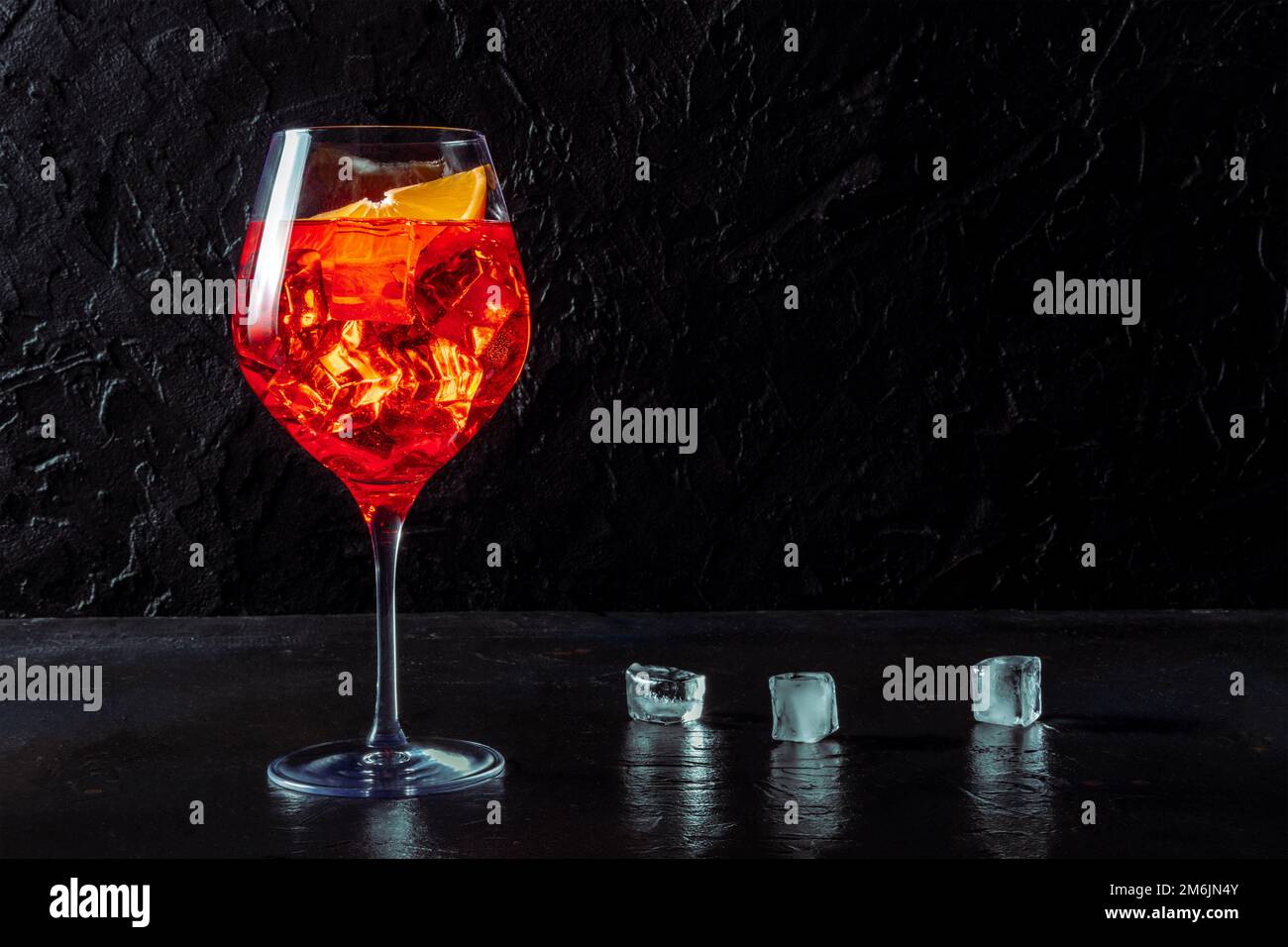 Aperol cocktail with a fresh orange and ice cubes, a side view on black ...