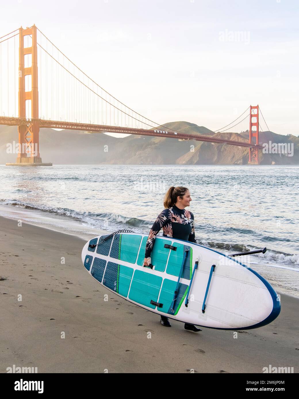Woman carrying paddleboard walking towards Golden Gate Bridge Stock ...