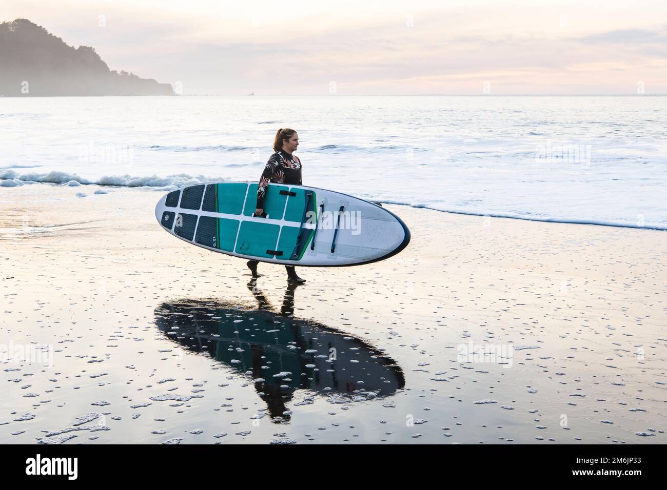 Woman carrying paddleboard hi-res stock photography and images - Alamy
