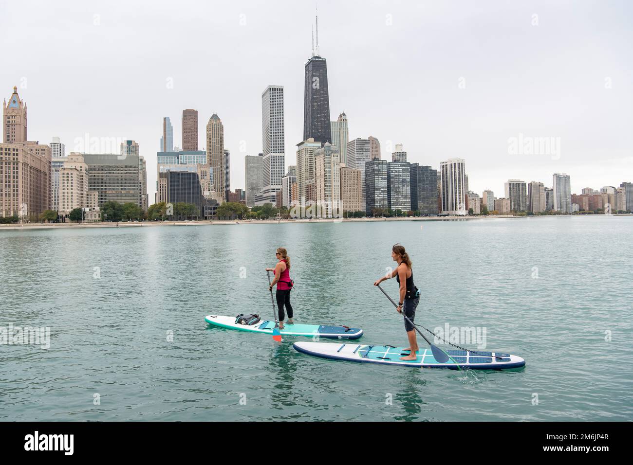 Side view of friends paddleboarding together in lake at sunset Stock ...