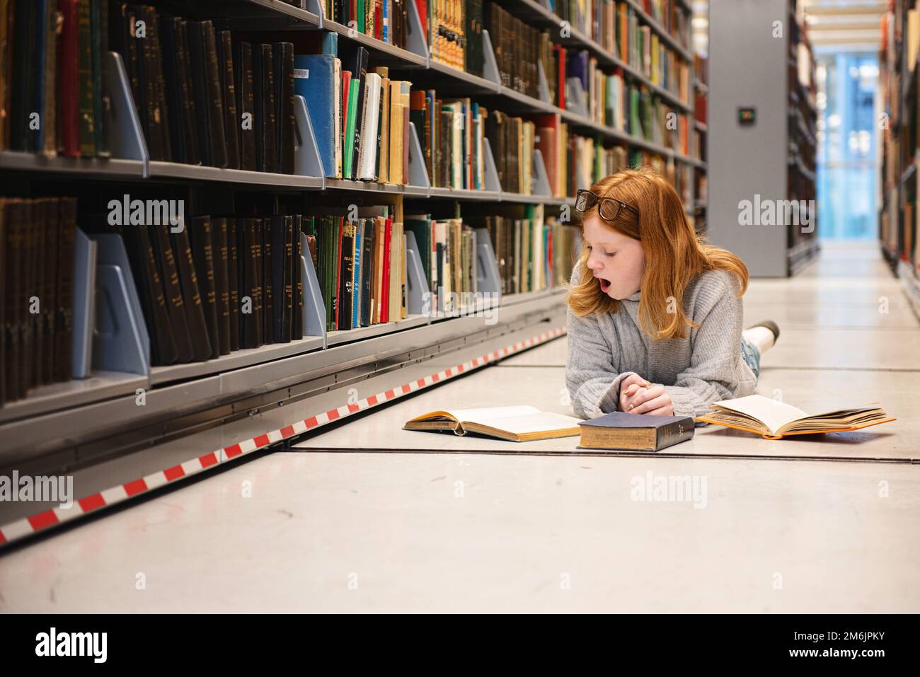 Tired teen girl studying at the library Stock Photo - Alamy