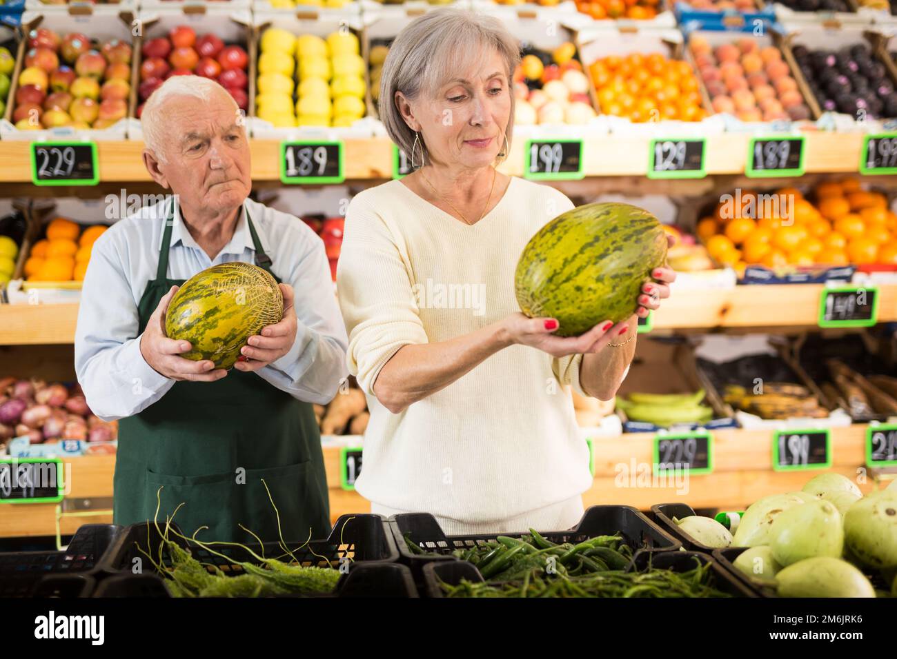 Grocery supermarket worker helping woman pick watermelon Stock Photo ...