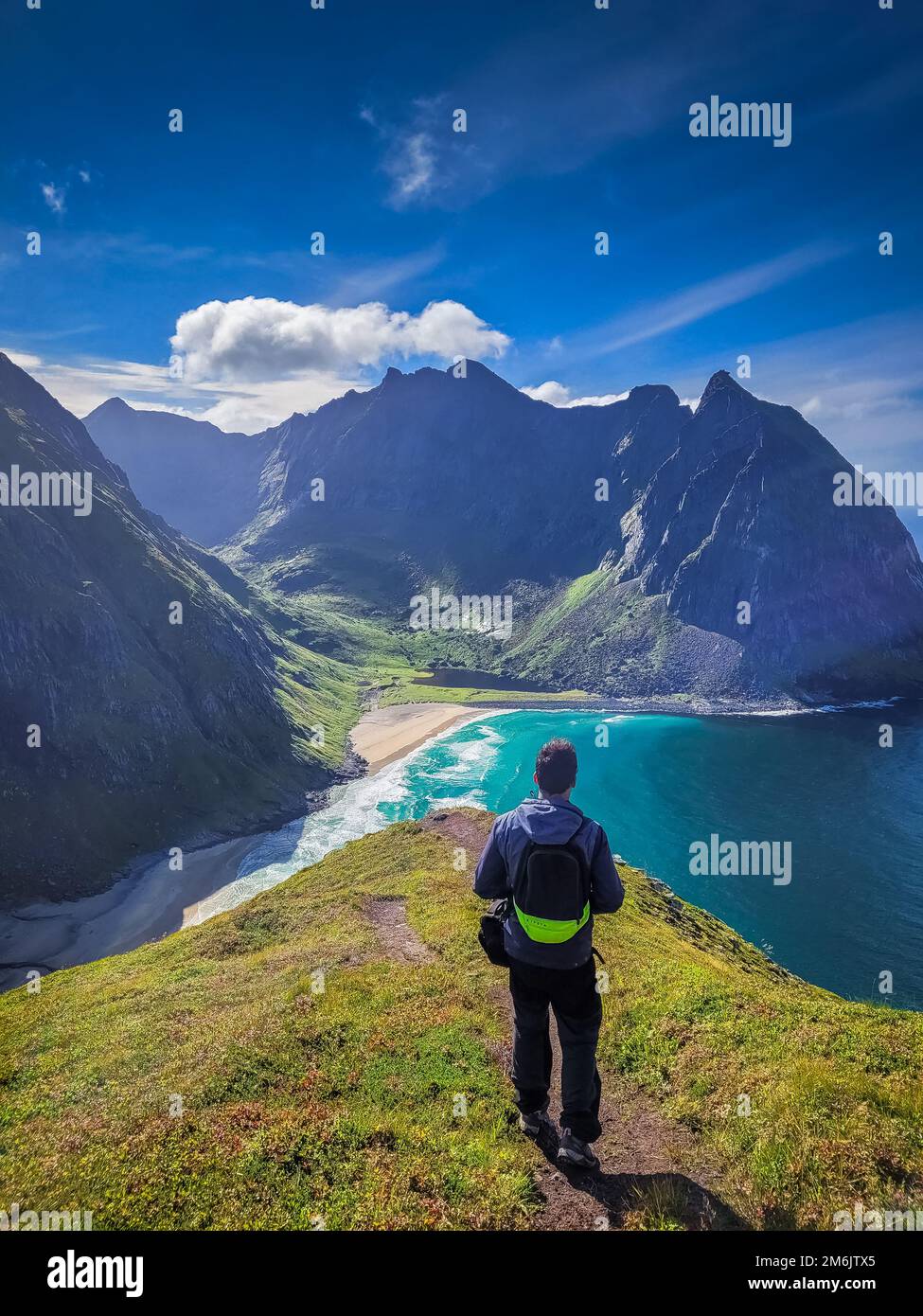 Adventurer hiking on mount Ryten with view over the Kvalvika Beach ...