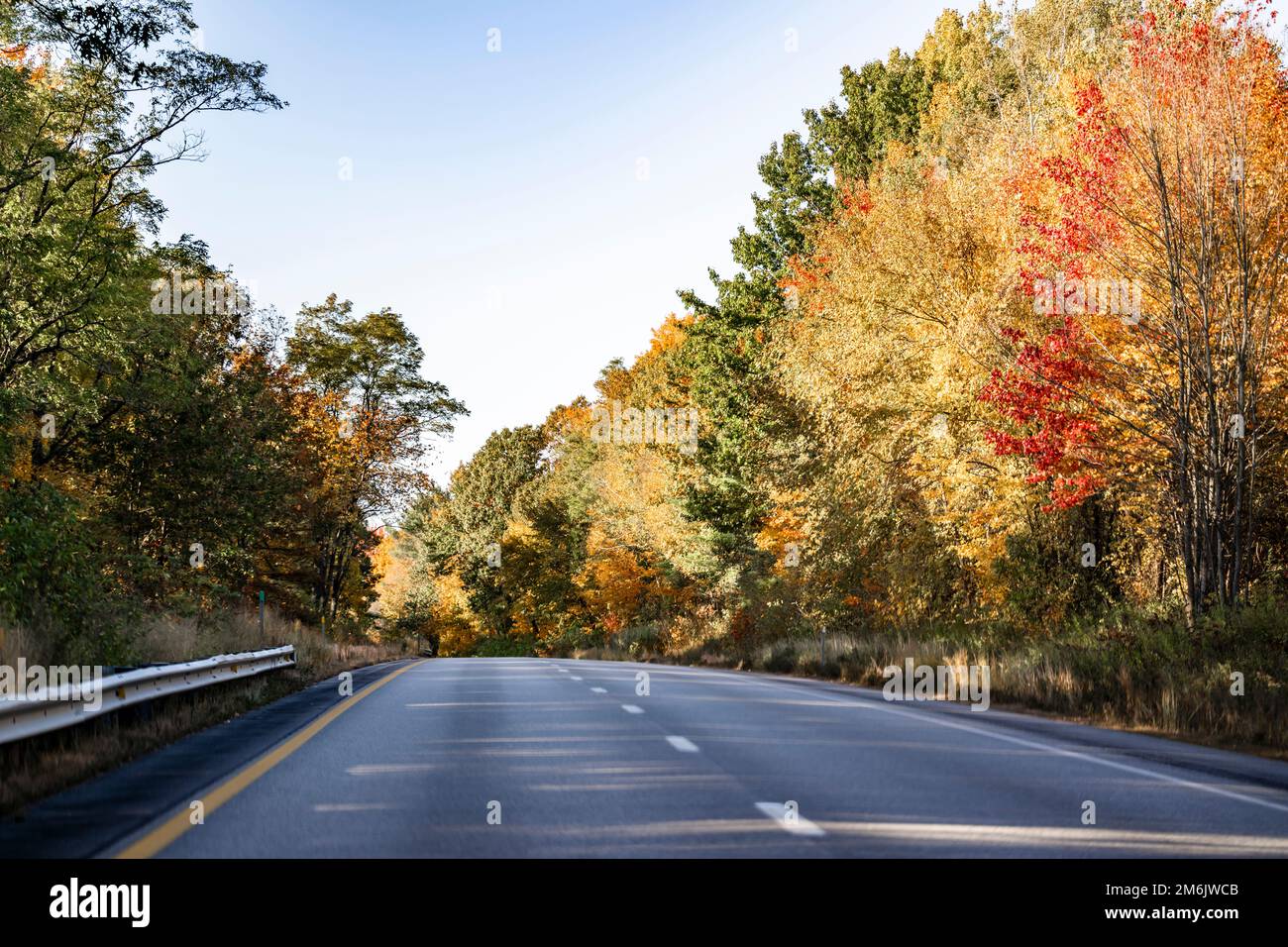 Scenic autumn landscape with a disappearing at horizon winding highway ...