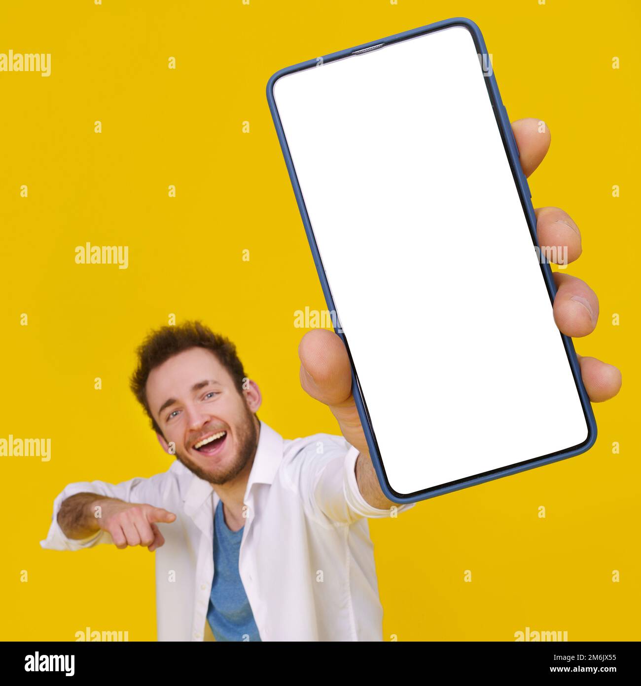 Young happy man holding smartphone showing a white empty screen check ...