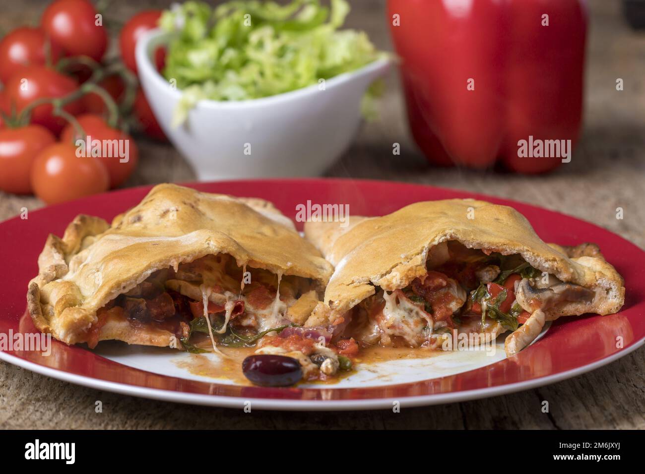Pizza Calzone on a red plate Stock Photo - Alamy