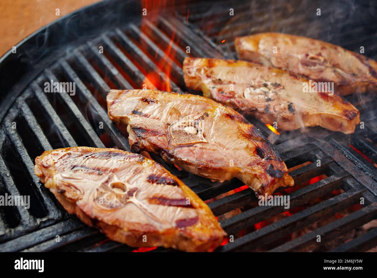 Raw lamb saddle back chop steak grilled as close-up on a charcoal grill ...