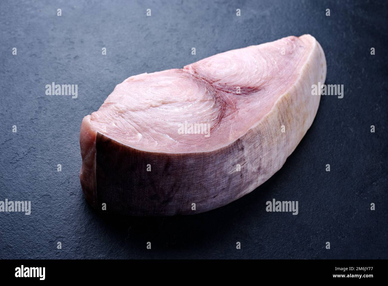 Raw swordfish steak offered as close-up on a black board with copy ...