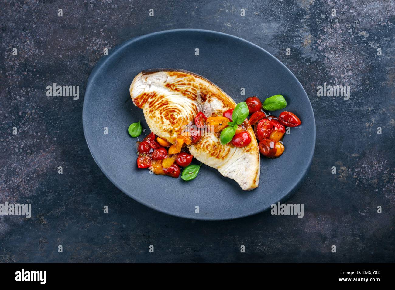 Roasted swordfish steak with tomatoes and paprika served as top view on ...