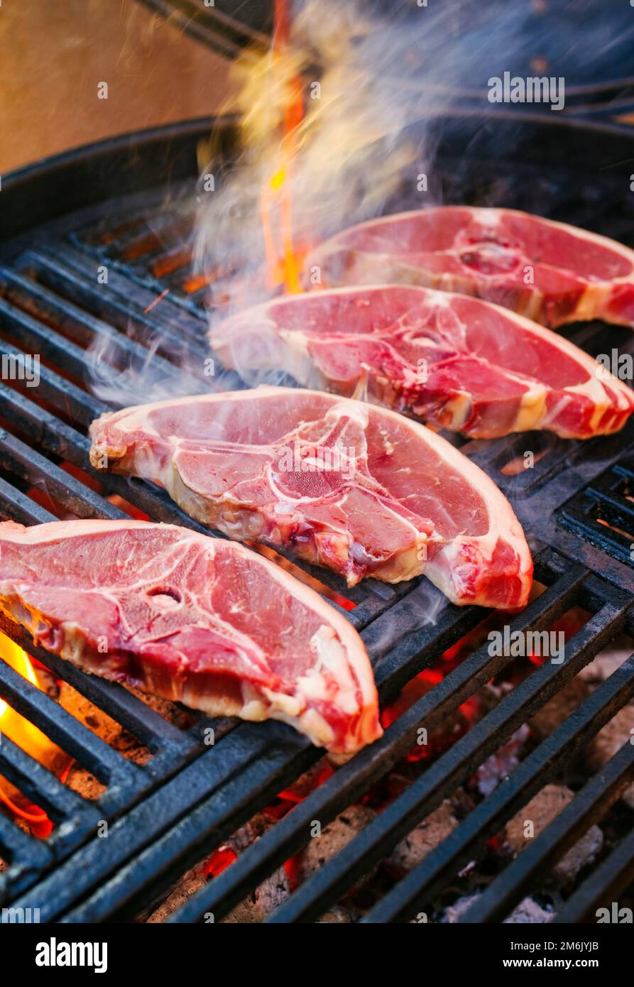 Raw lamb saddle back chop steak grilled as close-up on a charcoal grill ...
