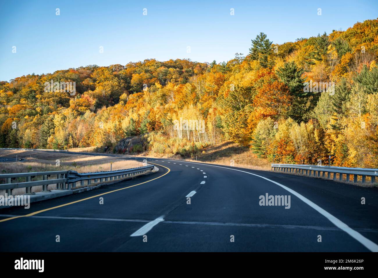 Scenic autumn landscape with a disappearing at horizon winding highway ...