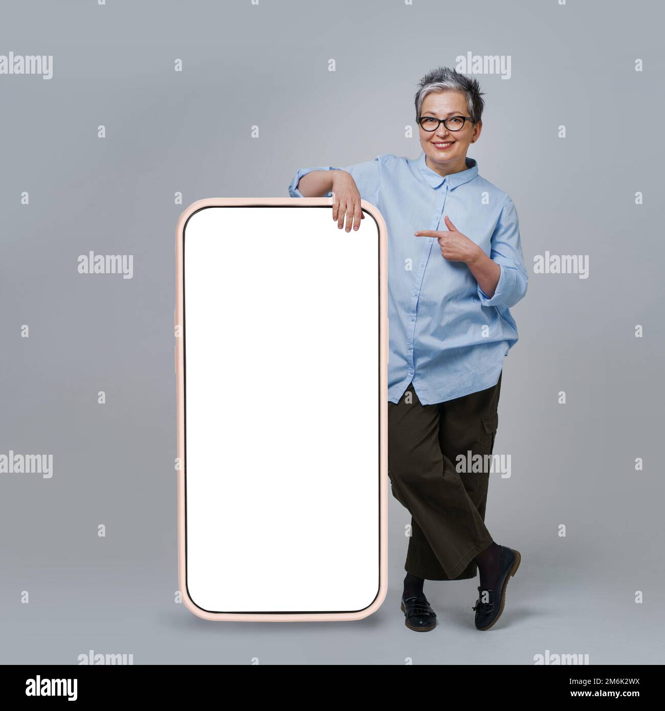 Mature grey hair woman pointing finger on screen of giant, huge ...