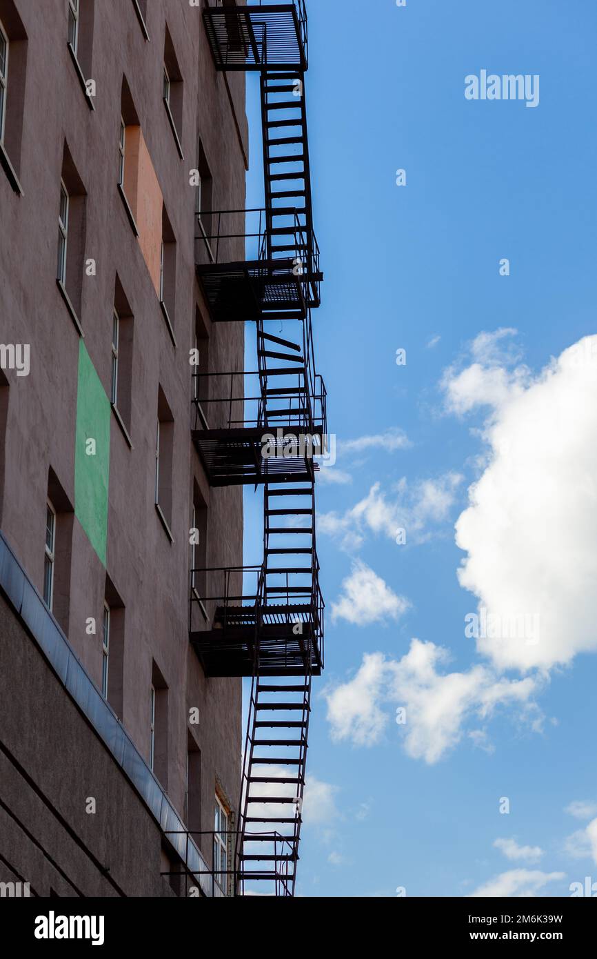 Silhouette of a fire escape on a high-rise building against a blue sky ...
