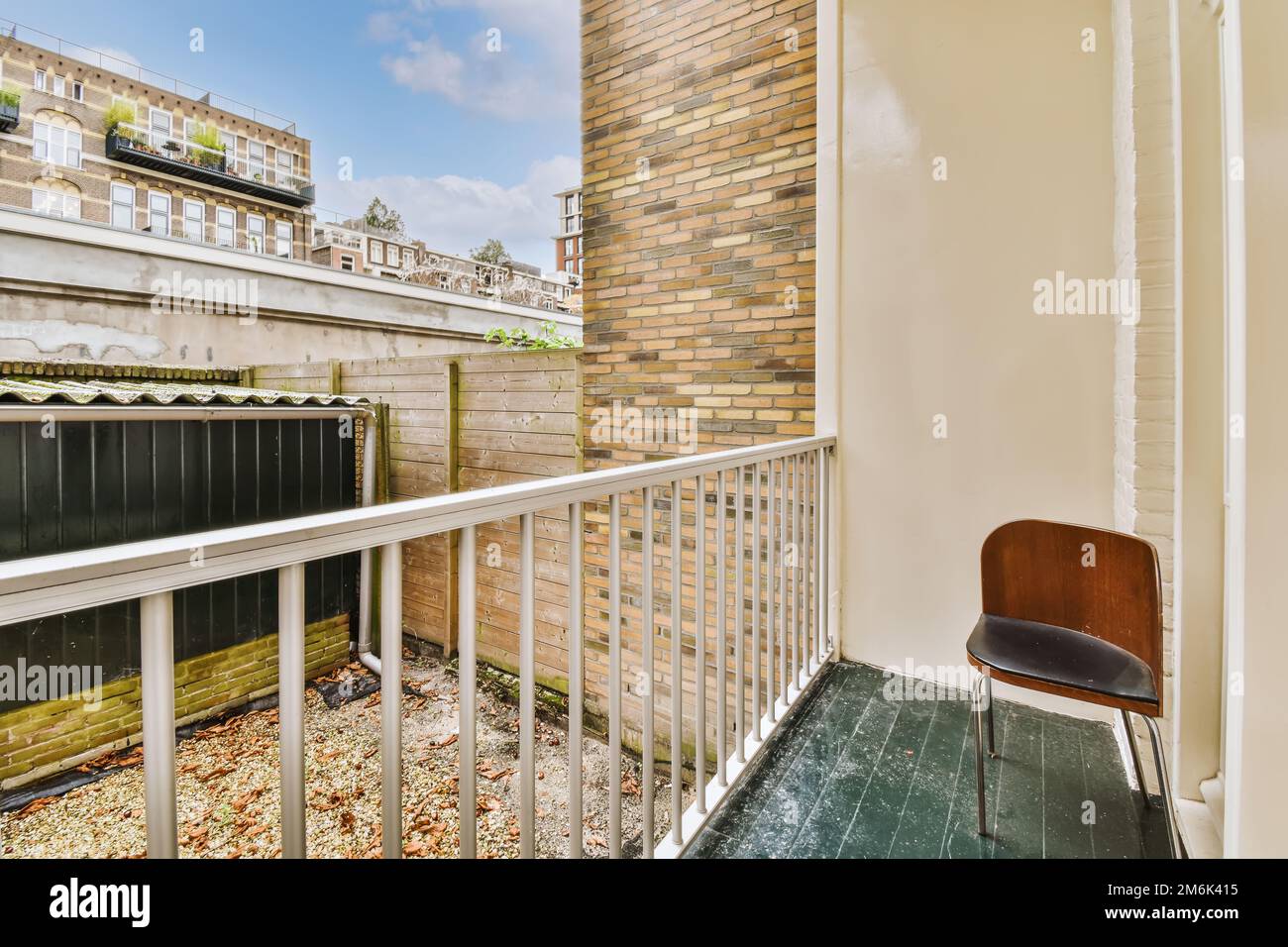 a balcony with a chair on the left hand side and brick wall to the ...