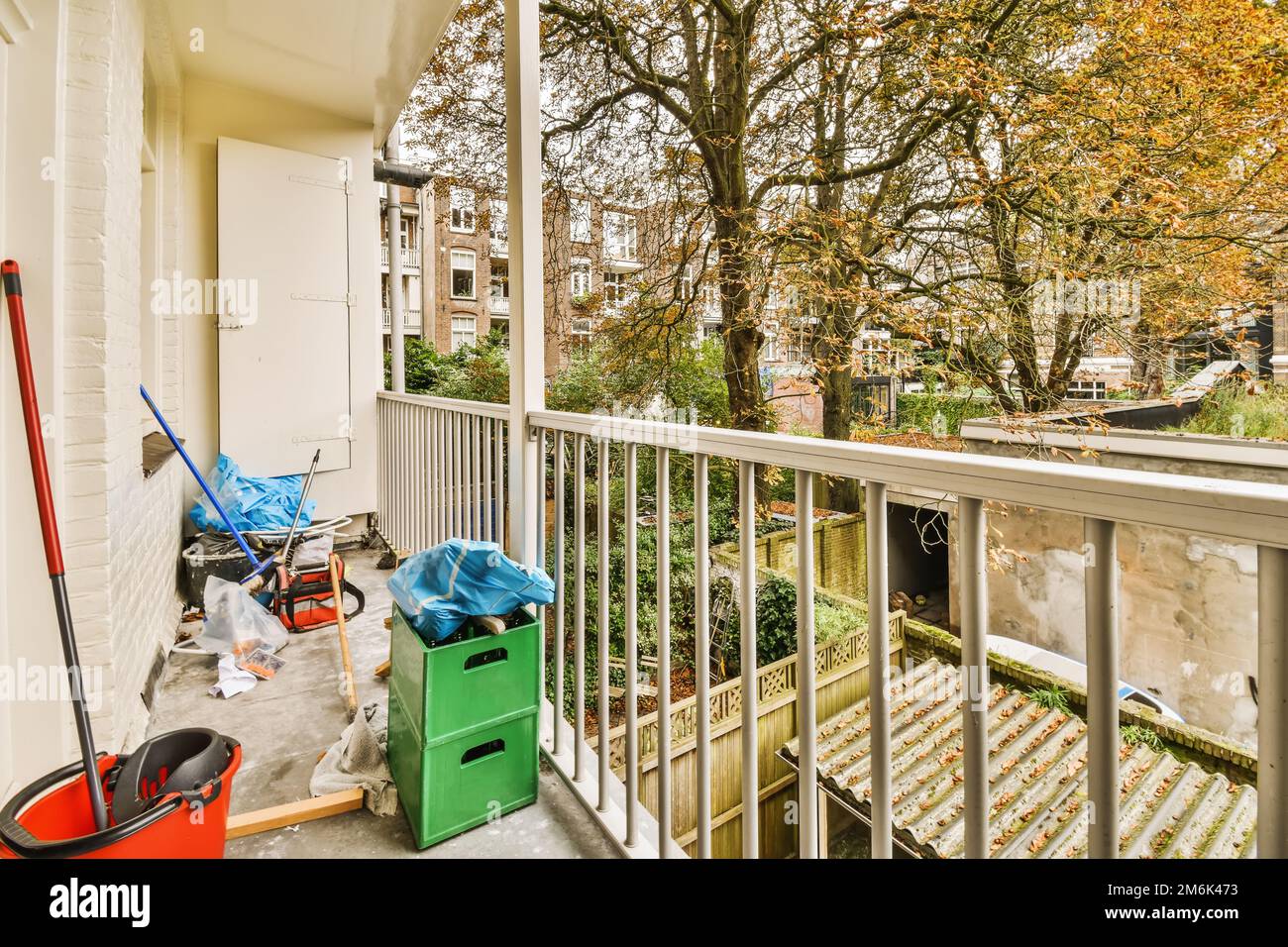 a balcony with trash bins and mops on the floor next to an open door ...