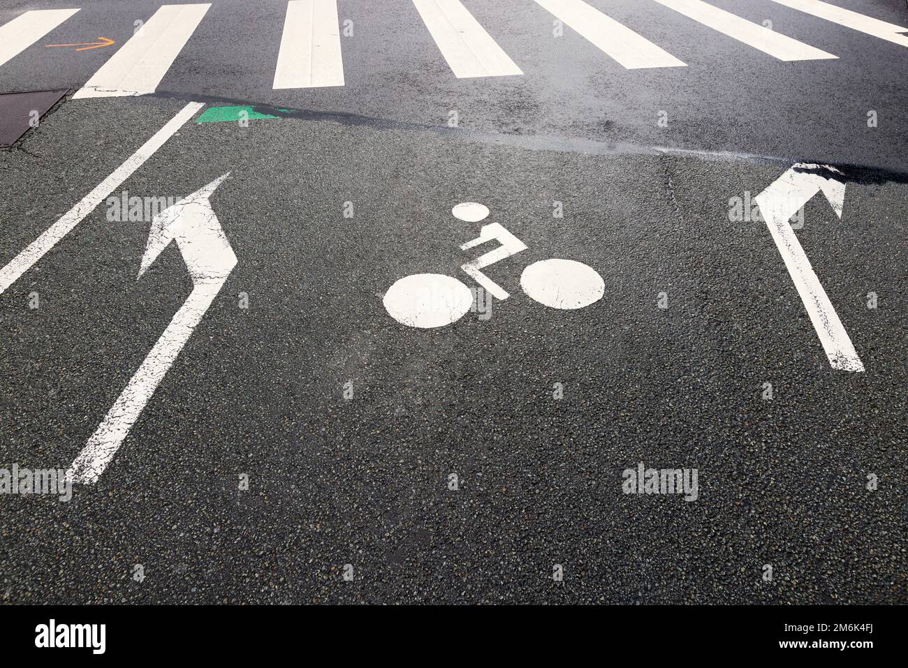 arrows, bicycle icon and zebra crossing on the asphalt of a city road ...