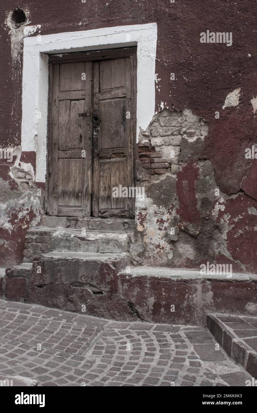 A weathered building with stone stairs and a wooden front door - the ...