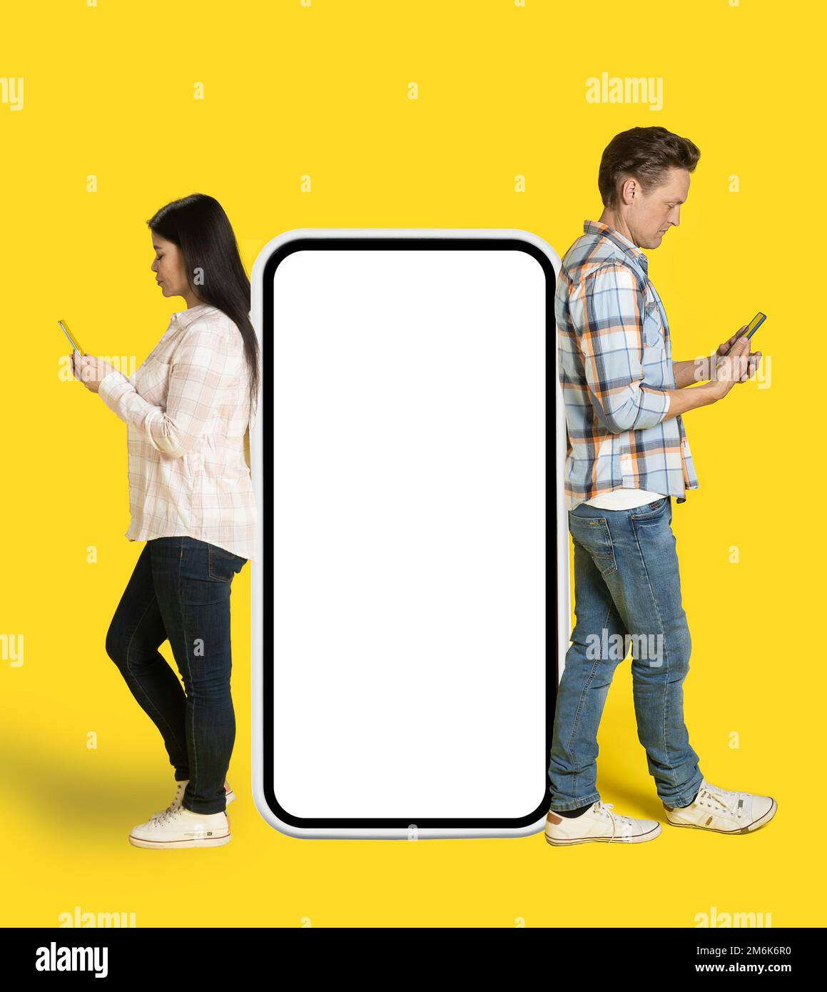 Asian woman and caucasian man standing leaned on huge smartphone with ...