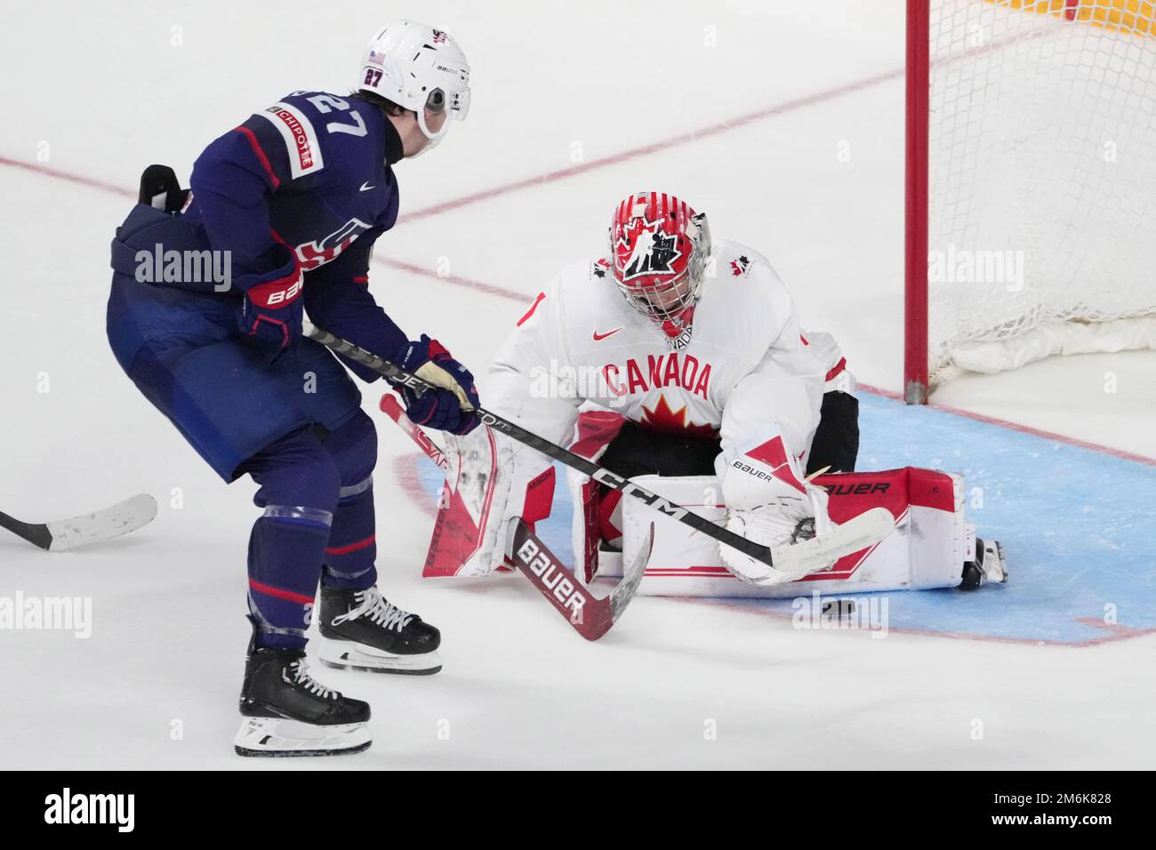 Canada goaltender Thomas Milic, right, makes a save on USA's Kenny ...