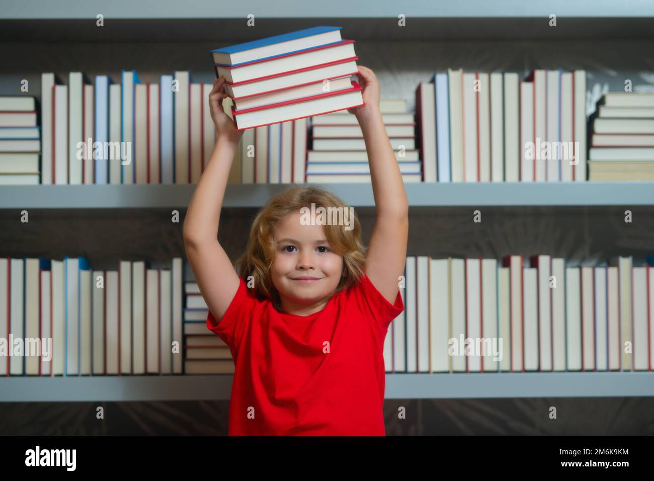 Excited school kid hold stack of books. Little student read book ...