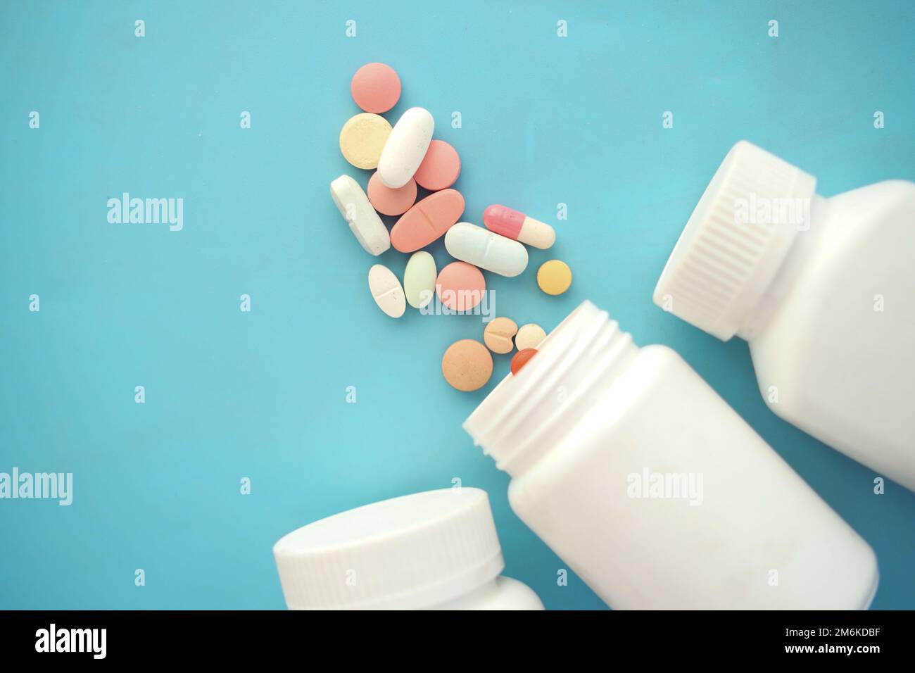 top view of many colorful pills and capsules spilling from container ...