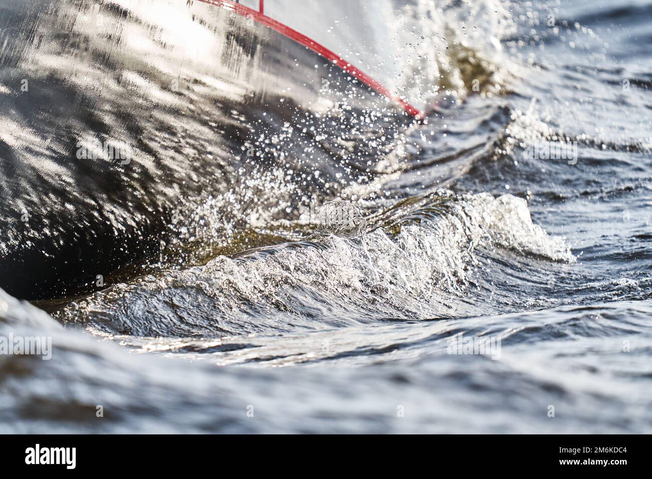 Water shatters against the glossy side of a sailing boat in a roll at ...