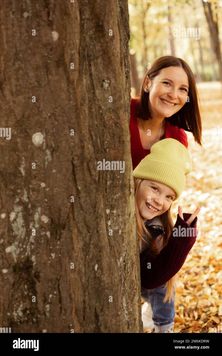 Portrait of family of young mother teenage girl standing behind tree ...
