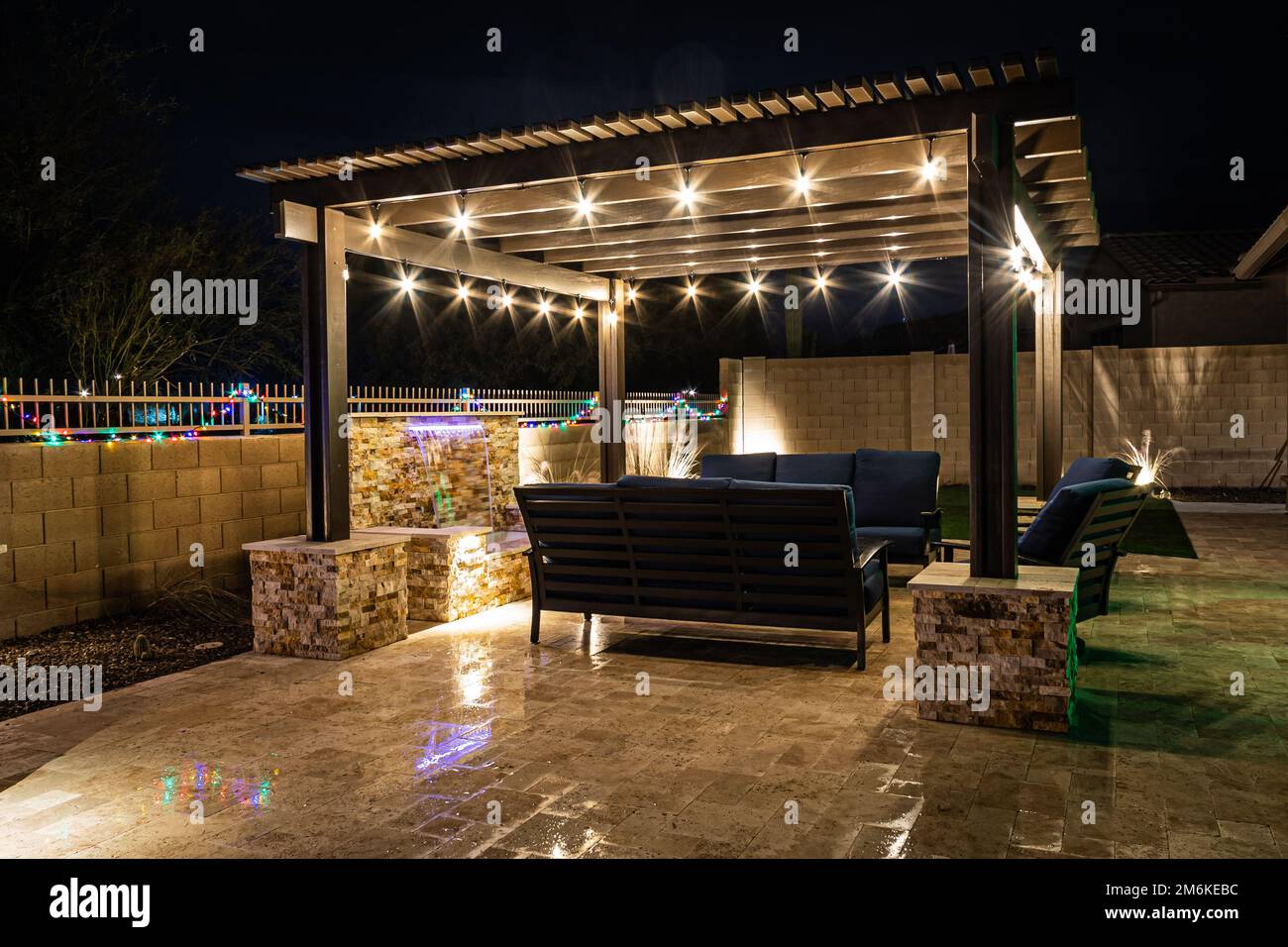 A resort style backyard at night with a waterfall, pergola, and a firepit at night Stock Photo ...