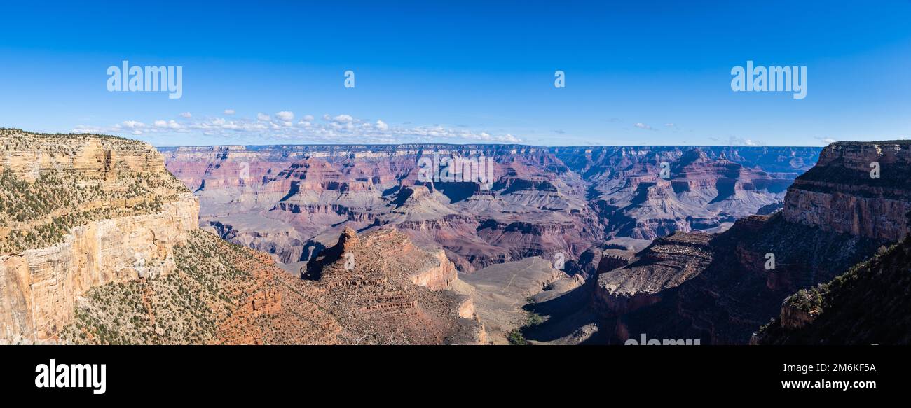 A panorama of the Grand Canyon in late morning sun with a blue, nearly ...