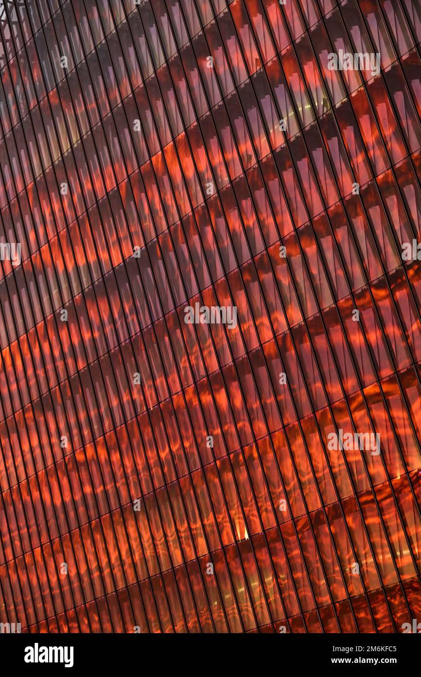 The glass and iron facade of huge skyscraper at sunset, steel, orange ...