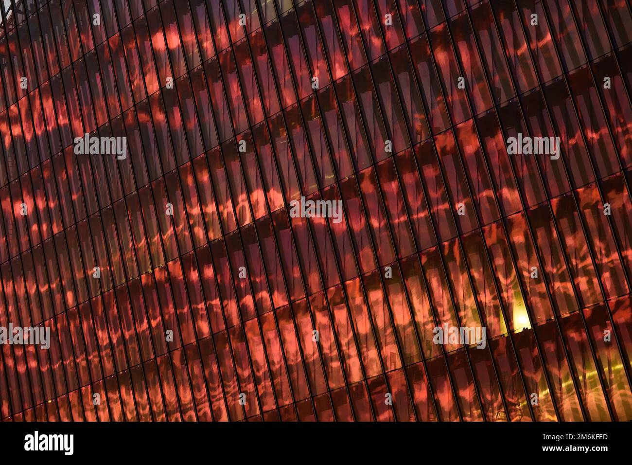 The glass and iron facade of huge skyscraper at sunset, steel, orange ...