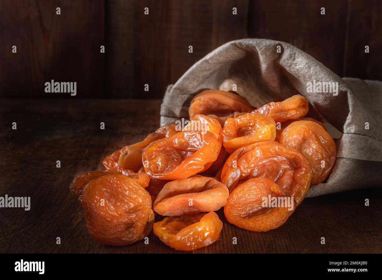 Dried apricots in a woven bag on a dark wooden background Stock Photo ...