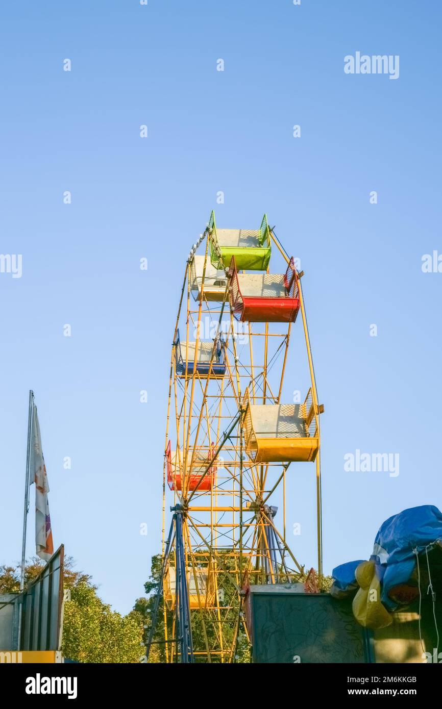 Old-fashioned ferris wheel with yellow, green and red seats against ...