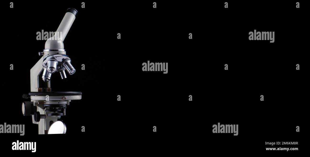 A microscope with three lenses on a black background. Concept, research ...