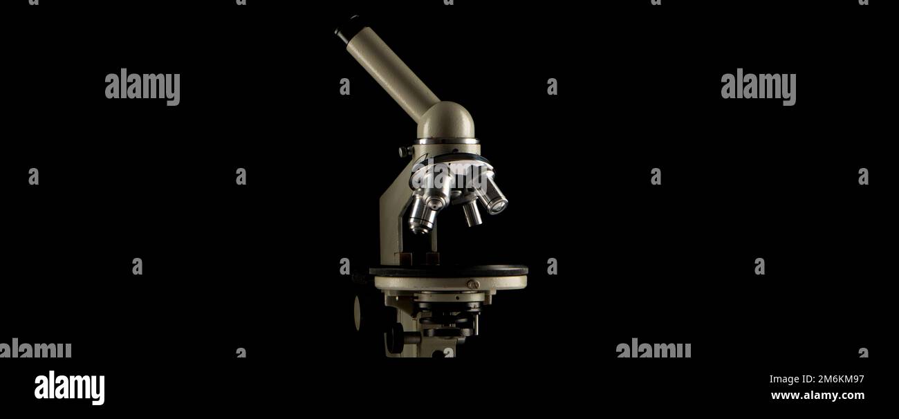 A microscope with three lenses on a black background. Concept, research ...