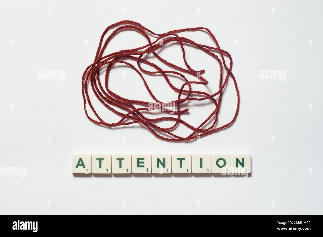 Attention formed of scrabble blocks with tangled thread Stock Photo - Alamy