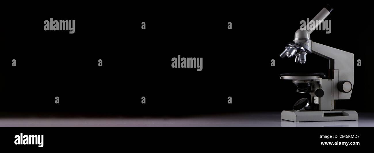 A microscope with three lenses on a black background. Concept, research ...