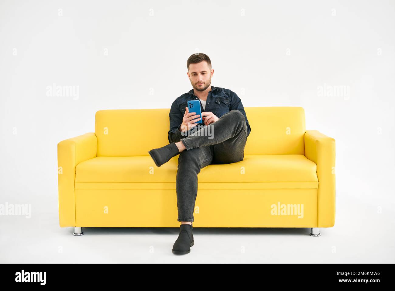 Relaxed man sitting on couch using hsi mobile smart phone Stock Photo ...